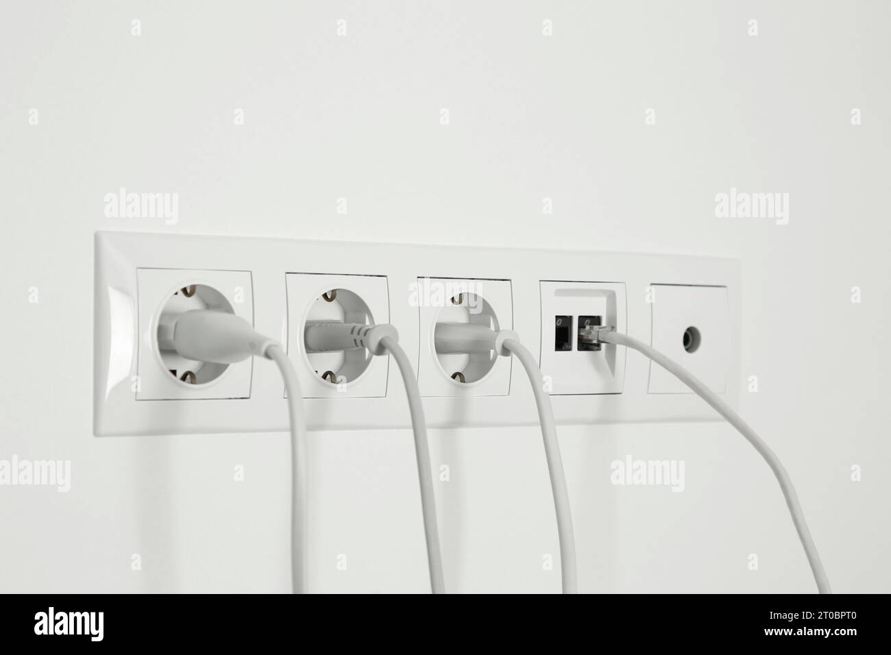 Many power sockets with plugs, ethernet and TV coax plates on white ...