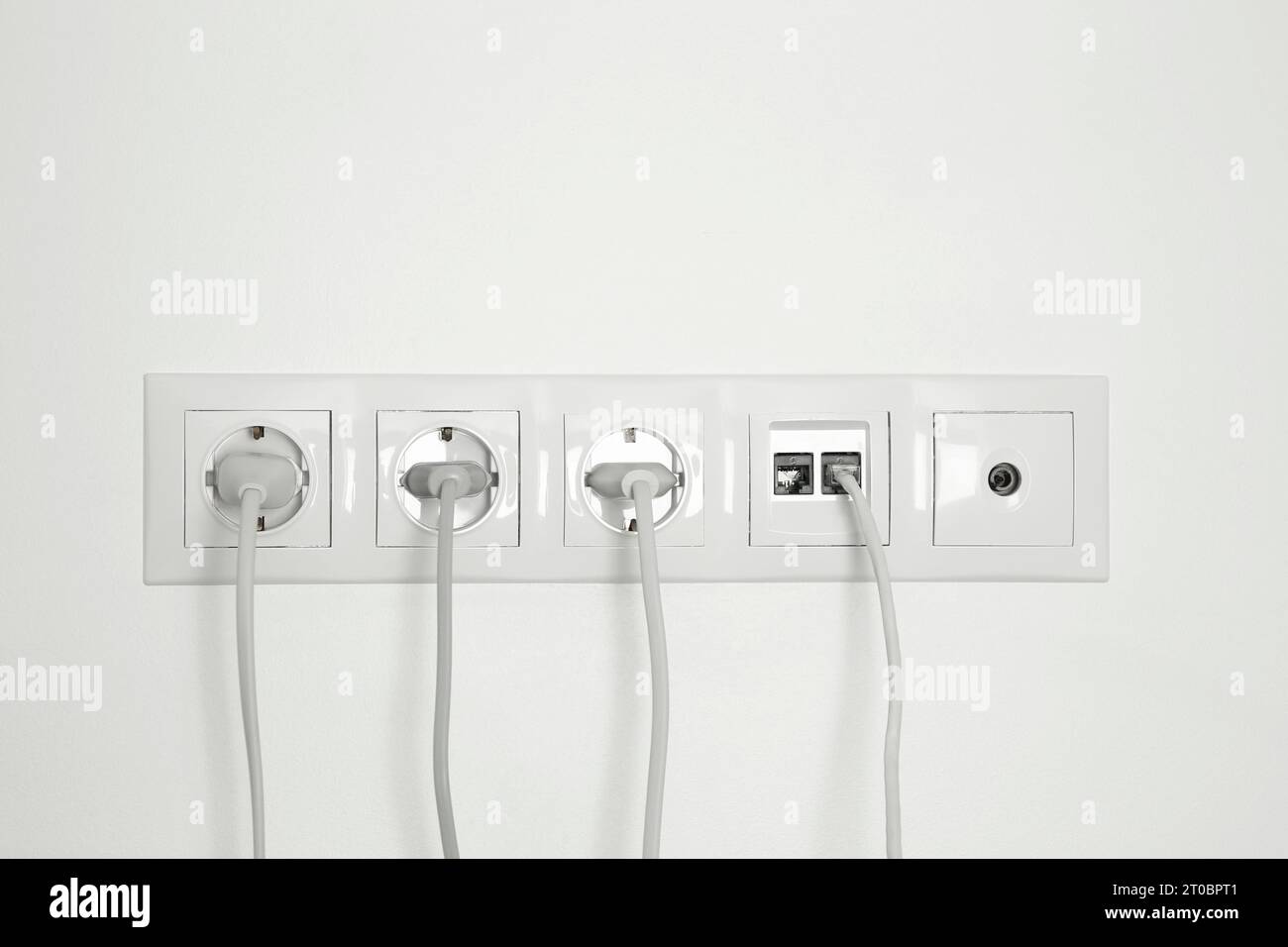 Many power sockets with plugs, ethernet and TV coax plates on white ...