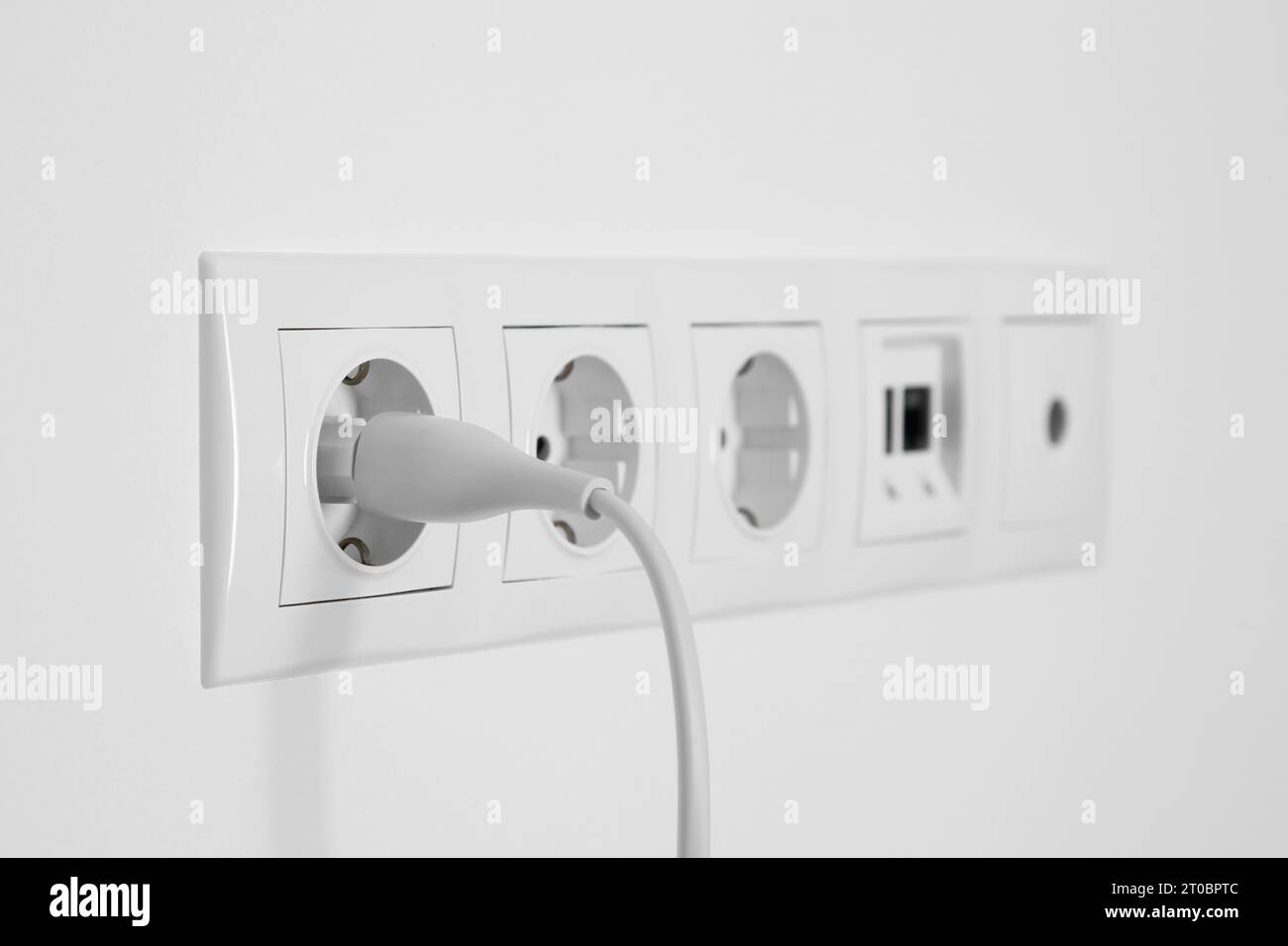Many power sockets with plug, ethernet and TV coax plates on white wall ...