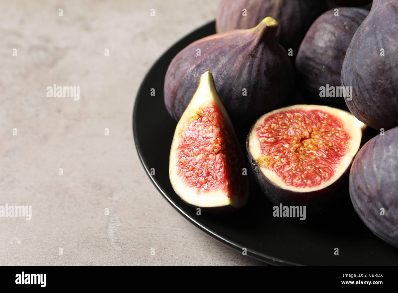 Whole and cut ripe figs on light grey textured table, closeup. Space ...