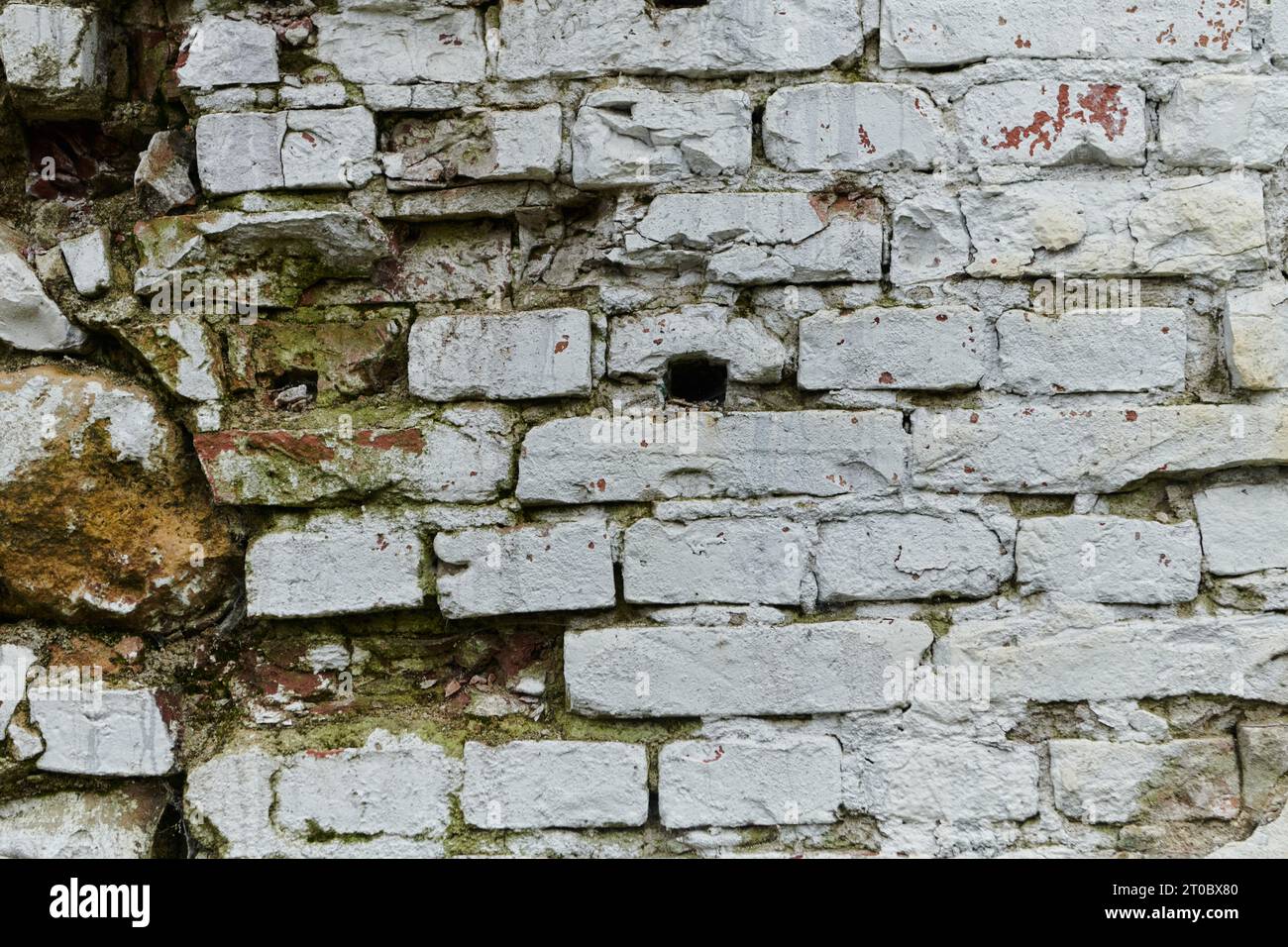 A weathered and aged stone brick wall, showing signs of decay and ...