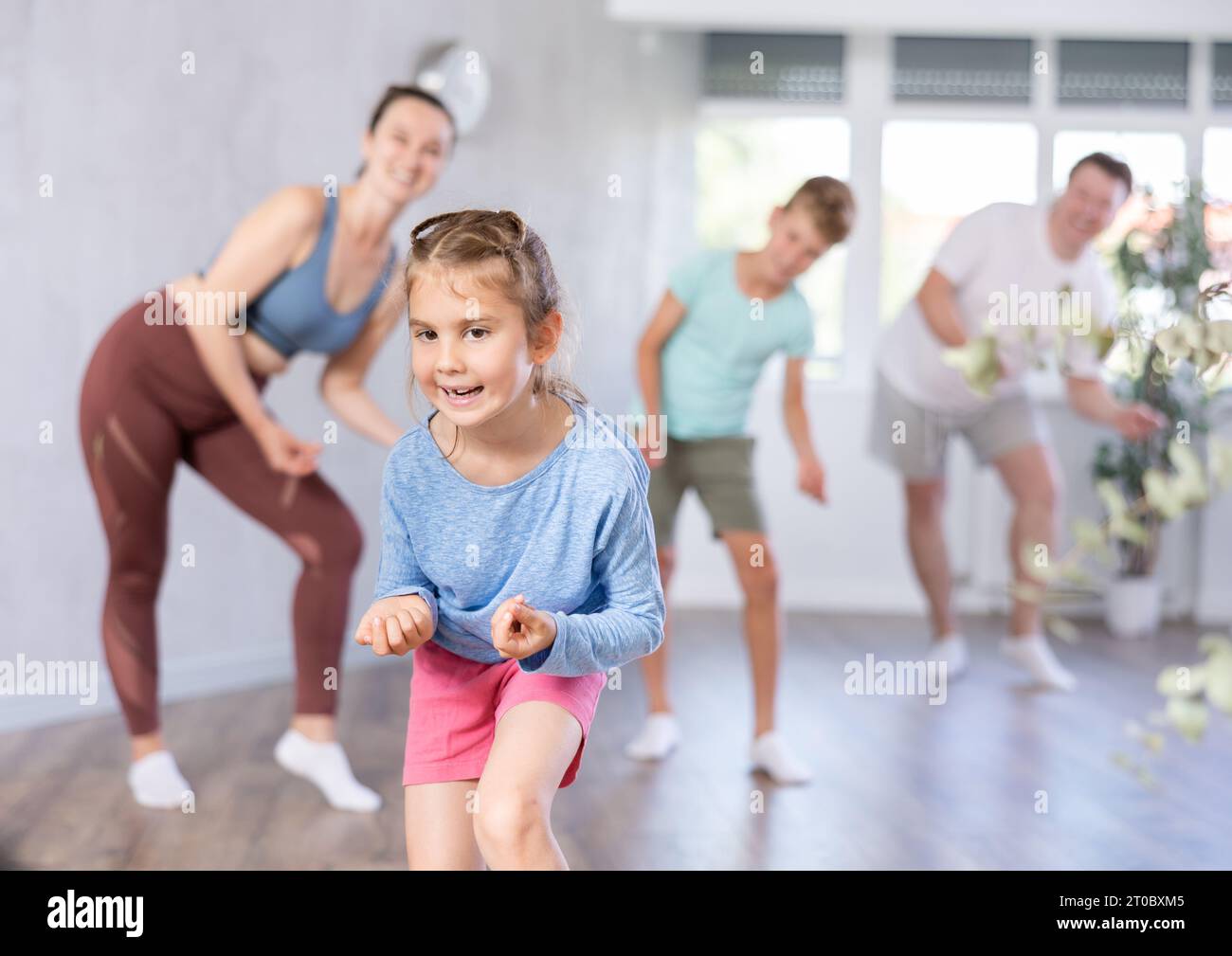 Cute little girl practicing dance movements with her family members ...