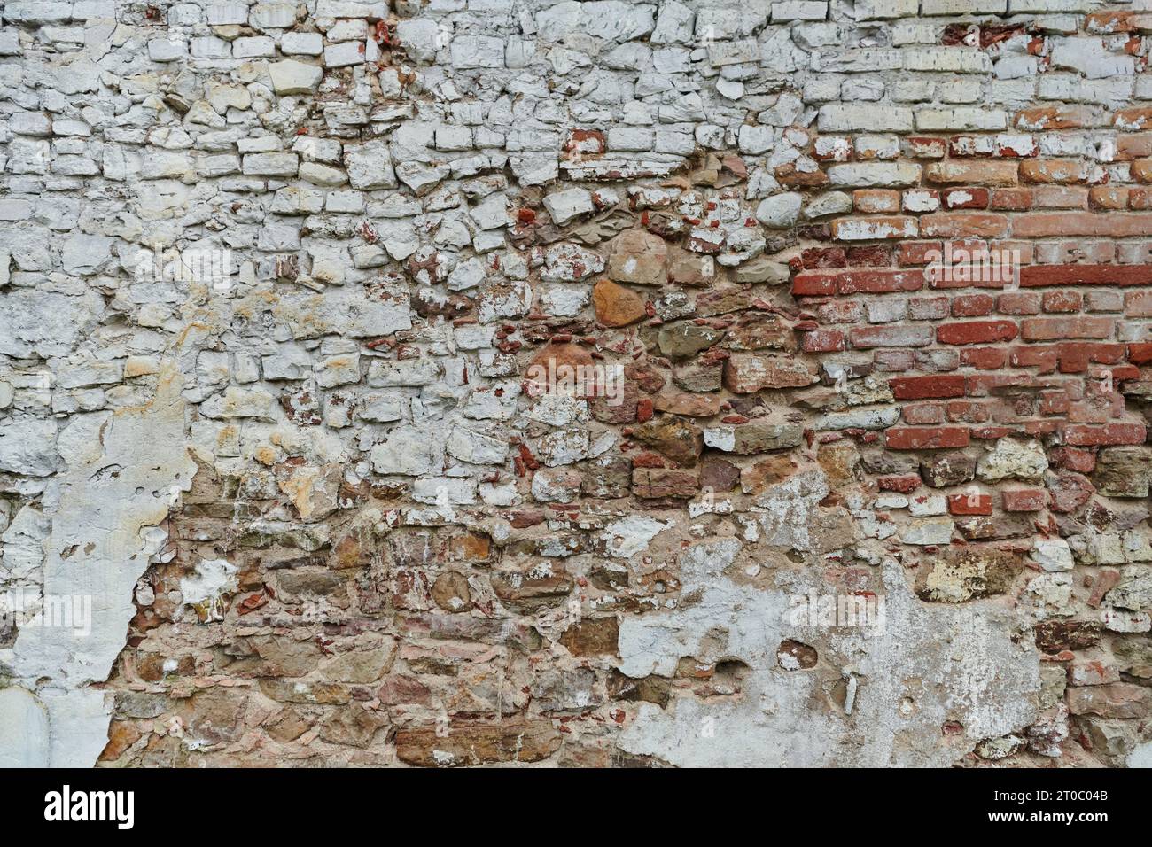 A weathered and aged stone brick wall, showing signs of decay and ...