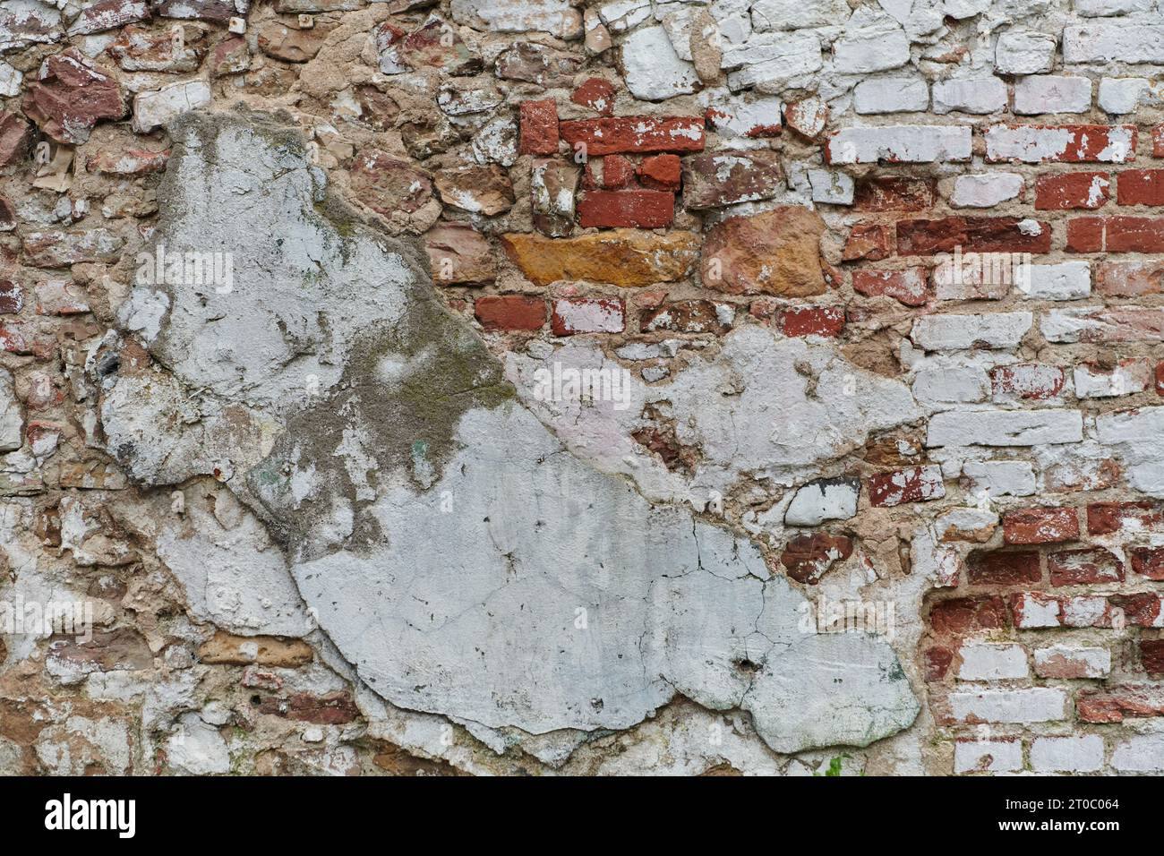A weathered and aged stone brick wall, showing signs of decay and ...