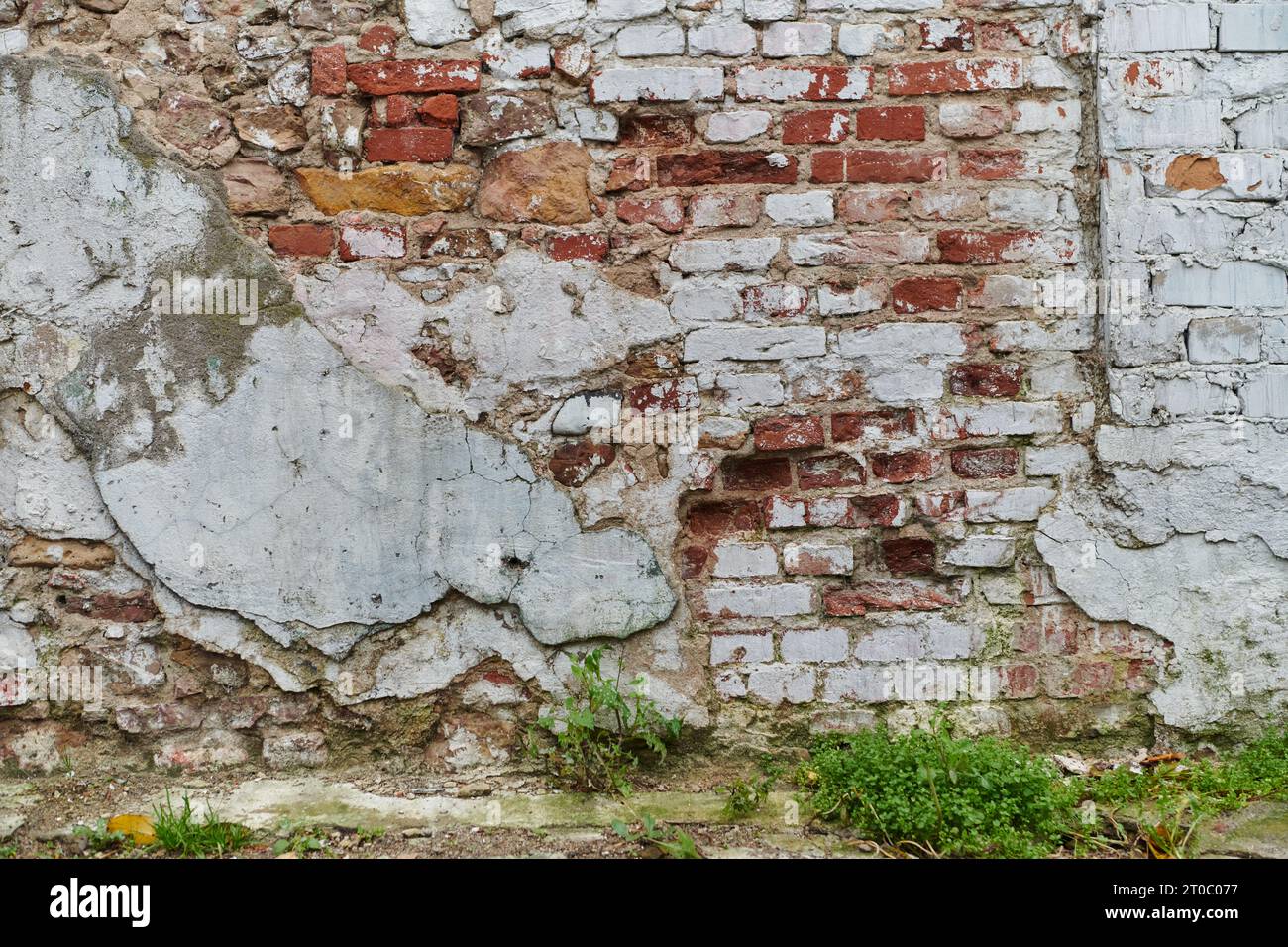 A weathered and aged stone brick wall, showing signs of decay and ...