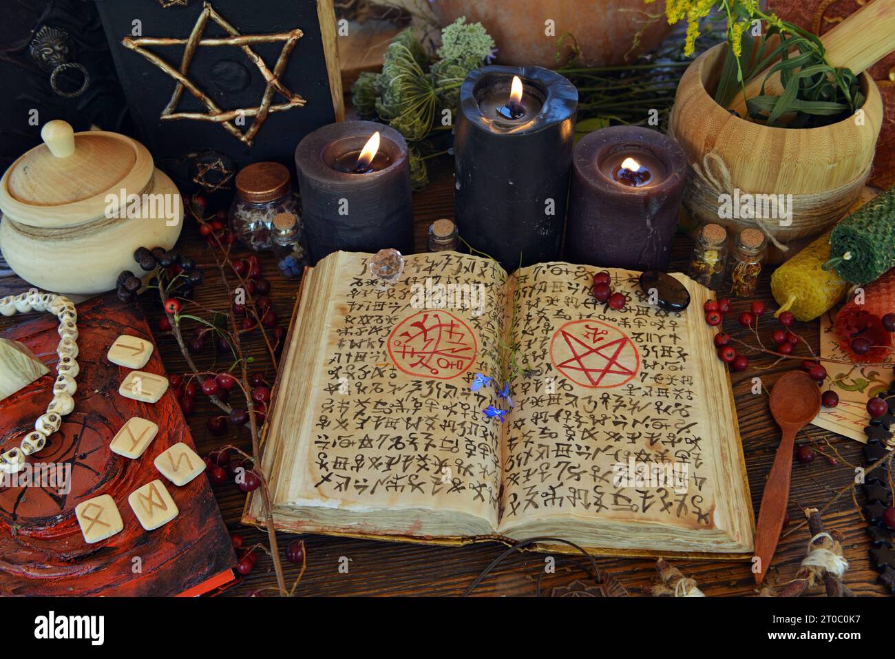Magic book of spells with candles and runes on witch altar table. No ...