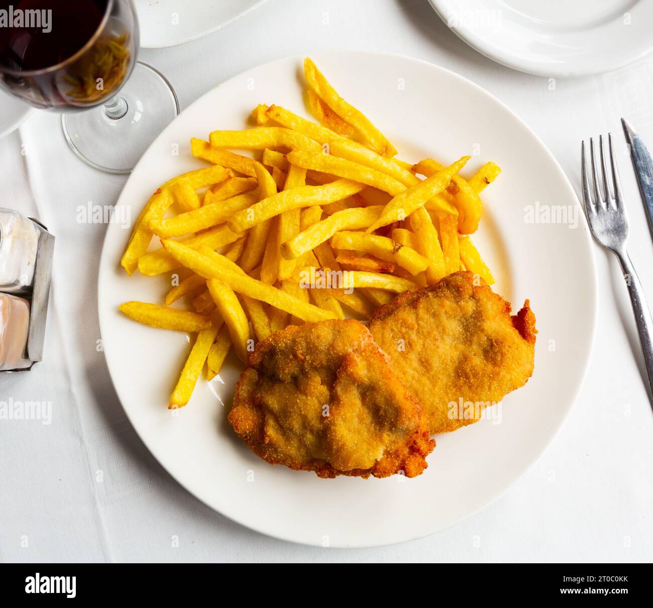Deep-fried pork filet in crispy coating with side dish of french fries ...