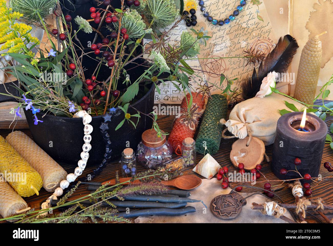Witch pot with herbs for potion, candles and magic objects on altar ...