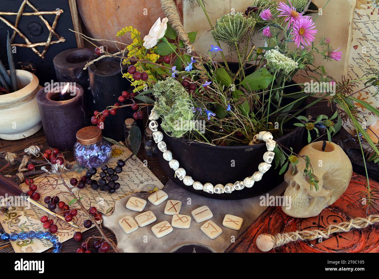 Witch pot with herbs, runes and candles on altar table. Occult ...
