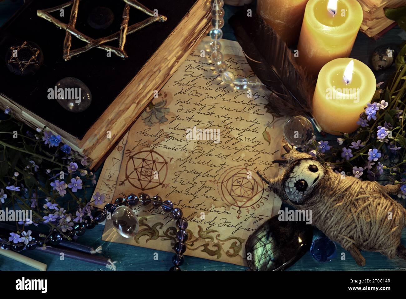 Voodoo doll with magic book of spells and candles on witch ritual table ...