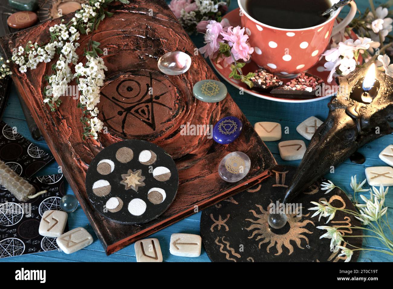 Old book of spells, flowers and runes on witch altar table. Occult ...