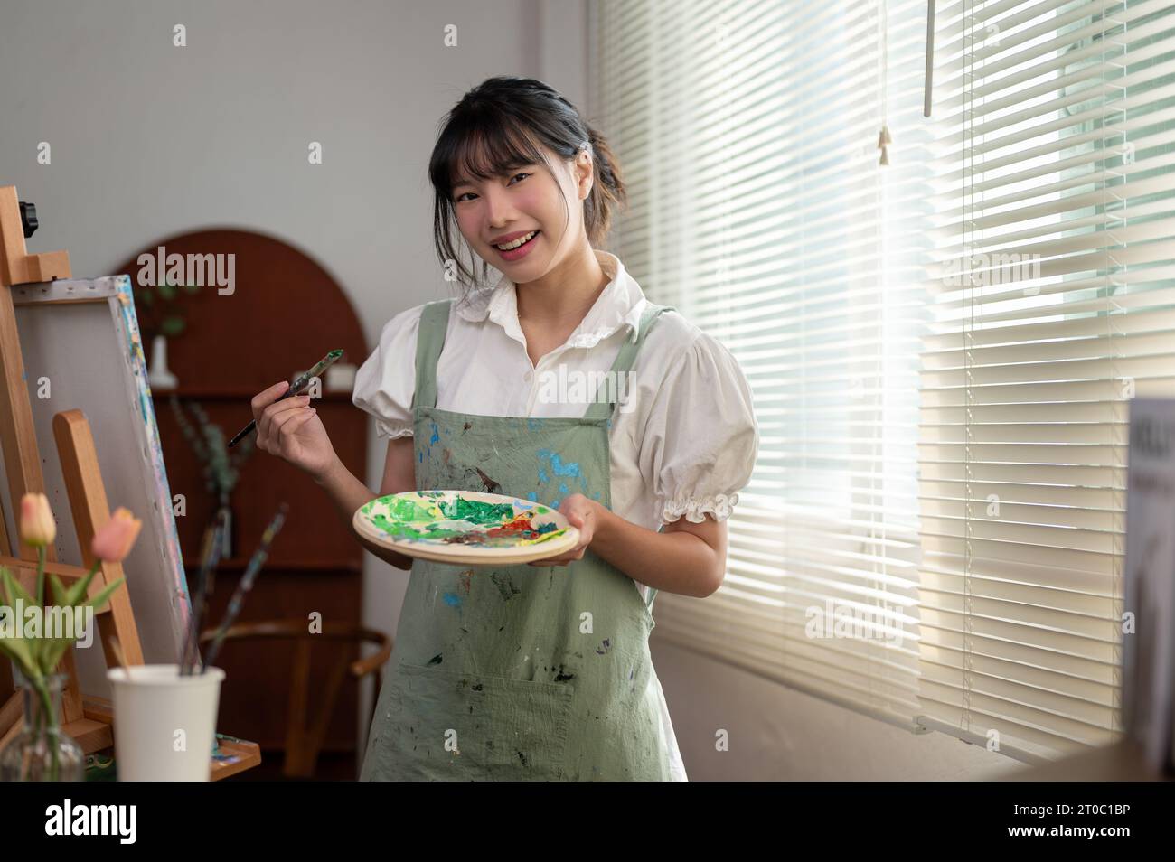 A portrait of a positive and creative young Asian female painter artist ...