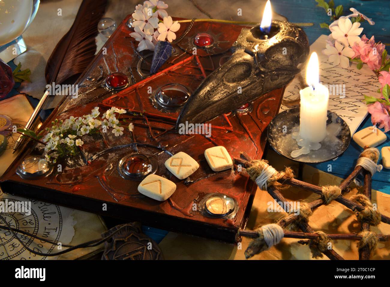 Black candle, runes and magic book of spell on witch ritual altar ...