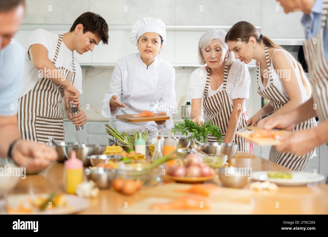 Chef in uniform teaches cooking class students how to clean and cut ...