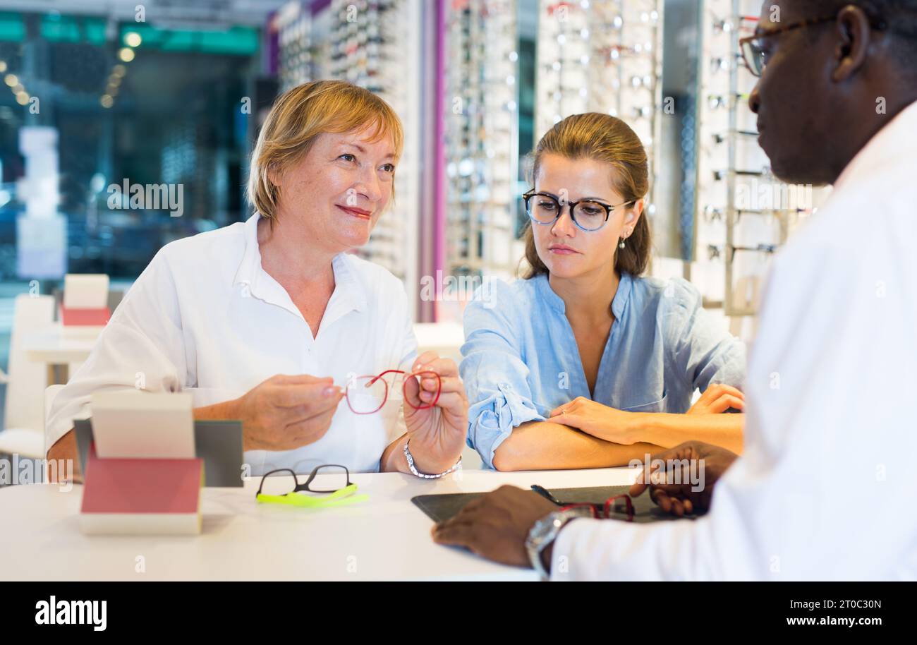Male and female opticians helping client to choose a spectacles Stock ...