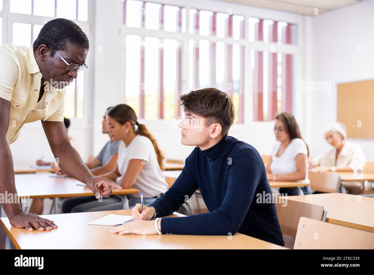 Professor explaining task solution to young man in college Stock Photo ...