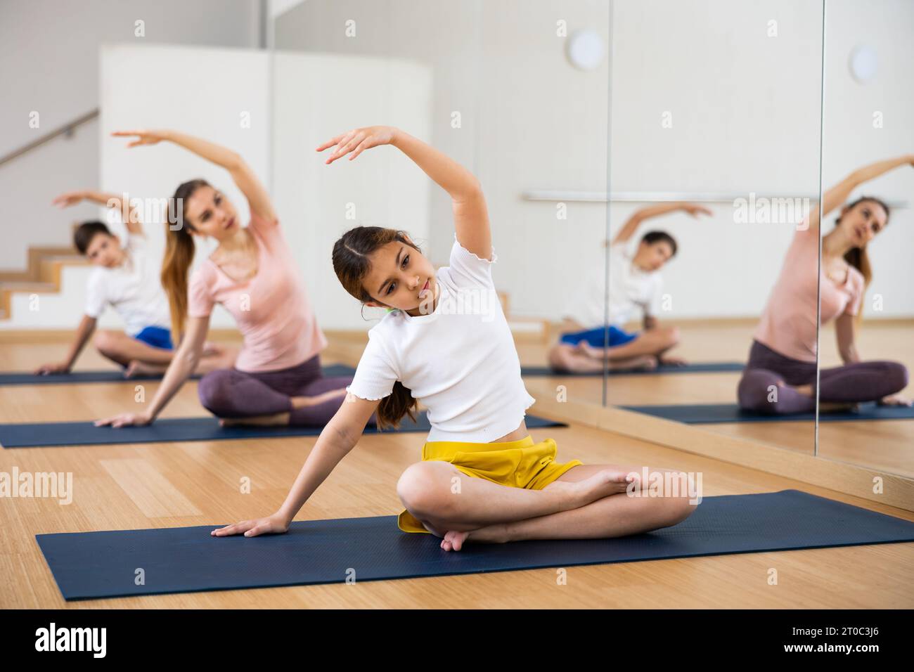 Preteen girl stretching in lotus position during family training Stock ...