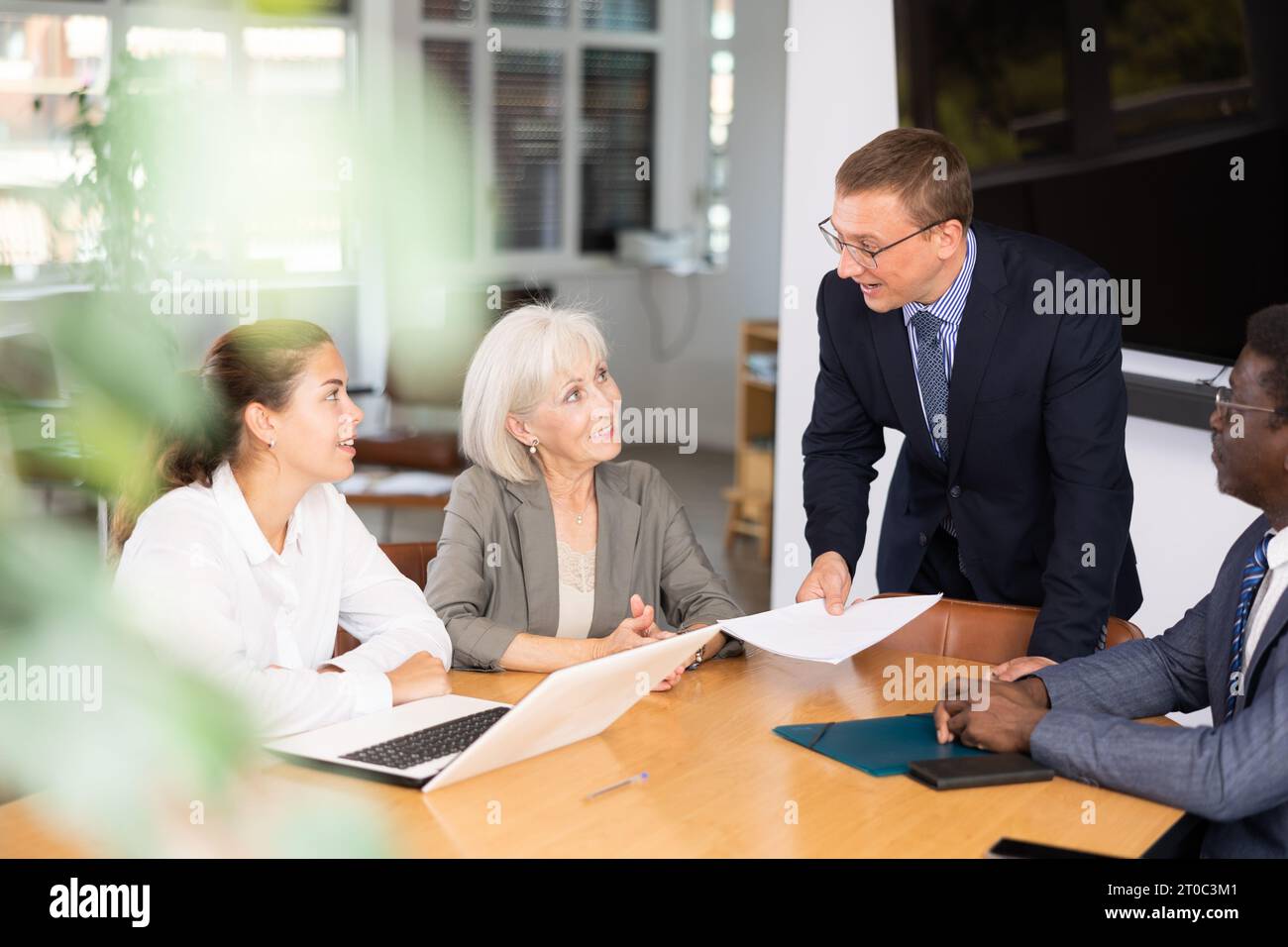 Positive business partners engaged in conversation sitting around table ...