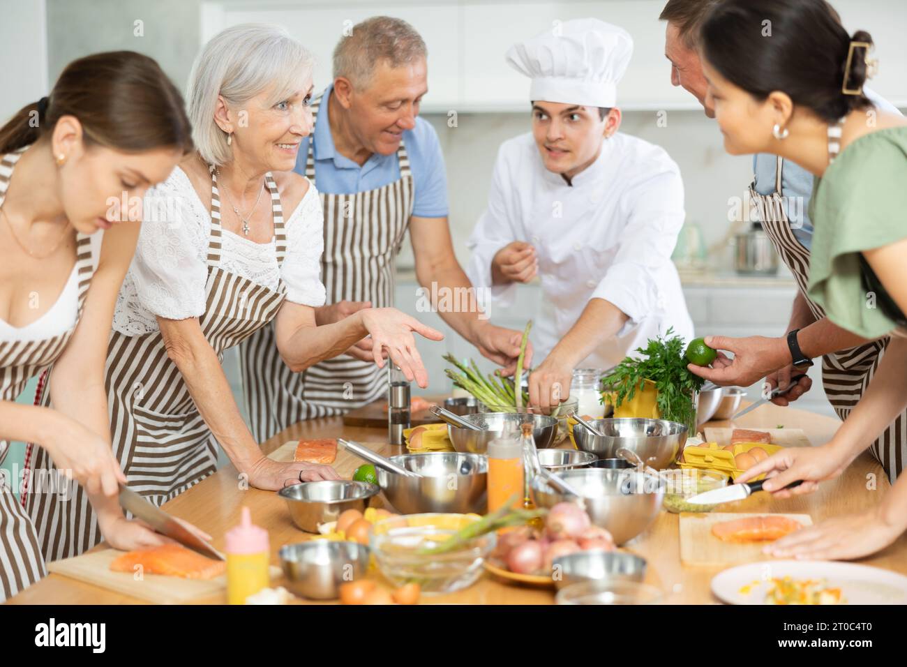 Chef in uniform teaches cooking class students how to clean and cut ...