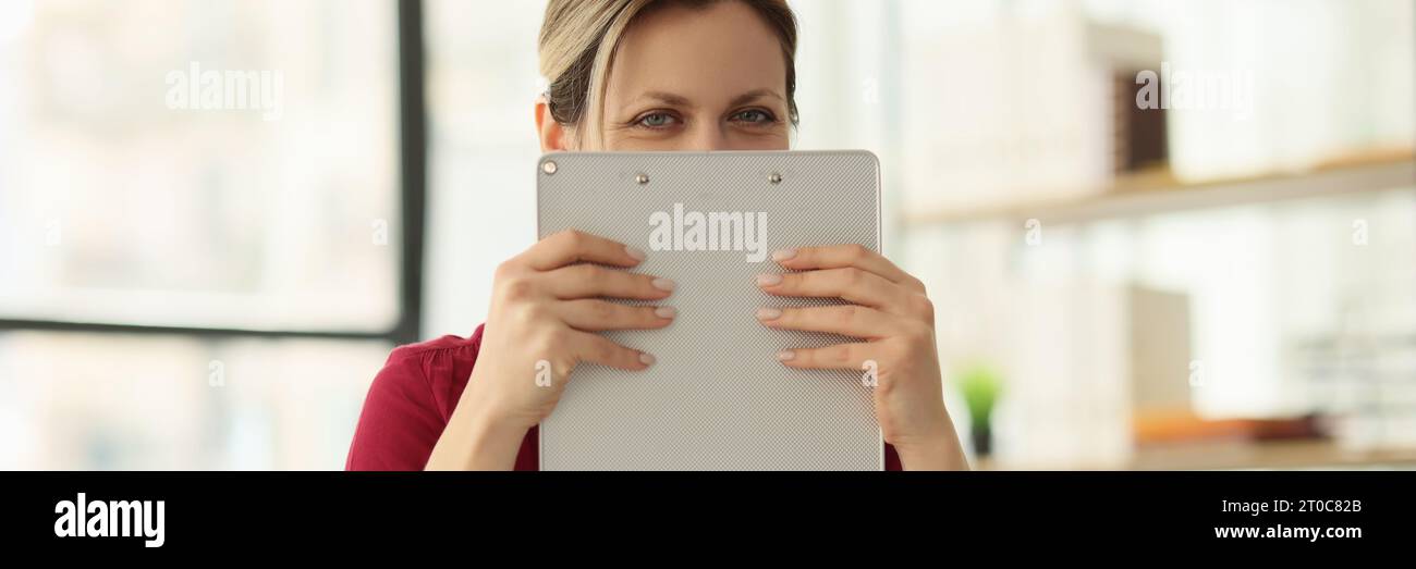 Positive employee hides face behind clipboard in office Stock Photo - Alamy