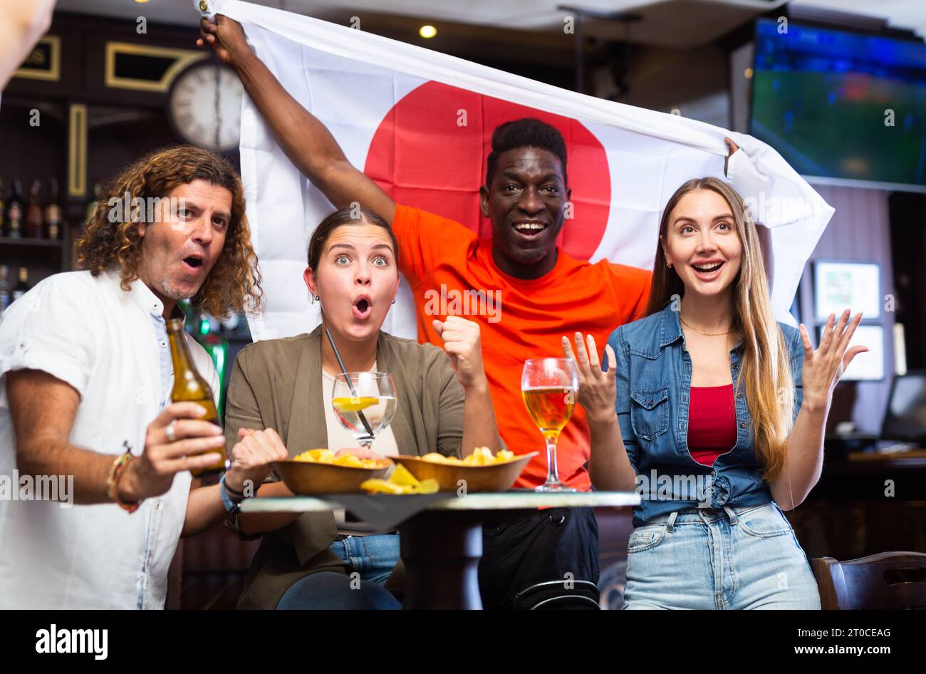 Group of cheerful people cheering for favorite Japanese sports team in ...