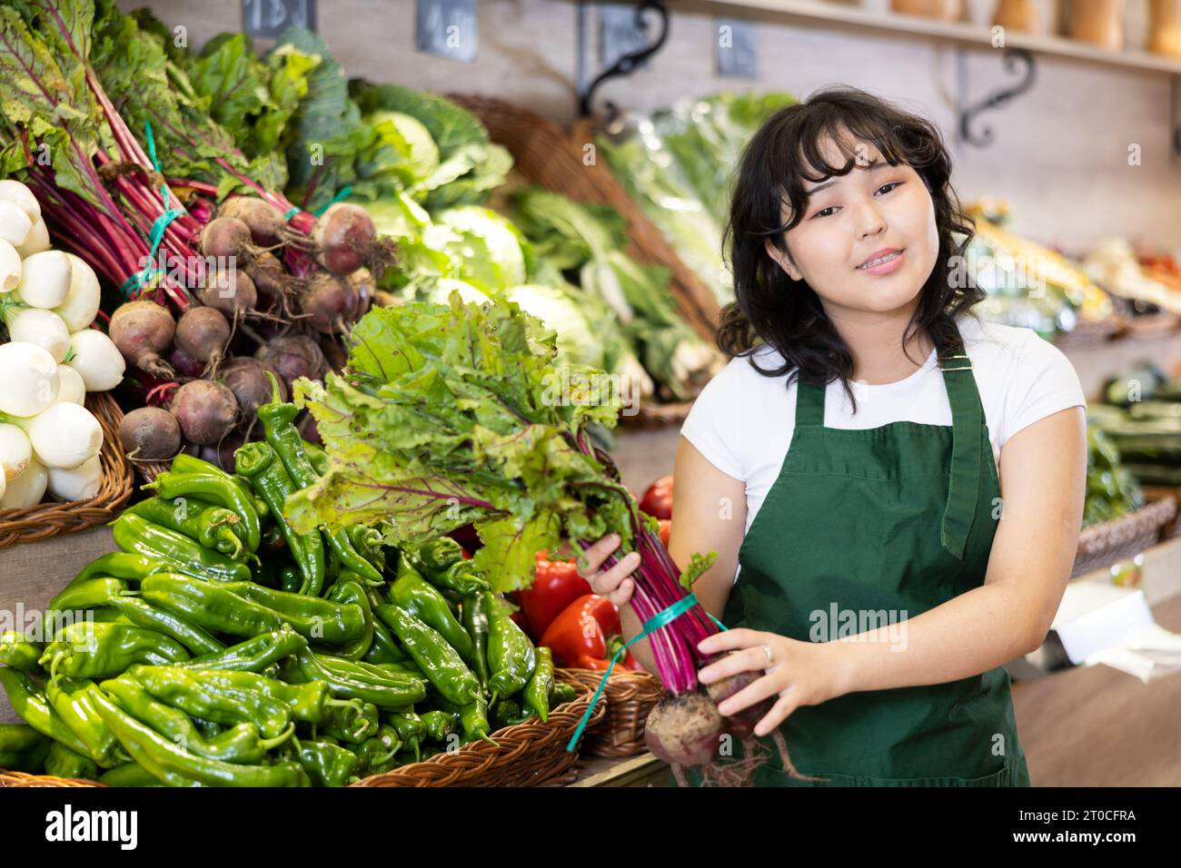 Hard-working girl supermarket employee puts fresh beets on the shelves ...