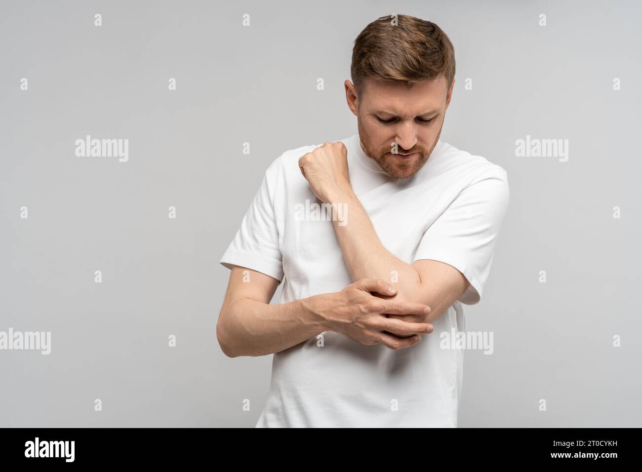 Middle aged man touching hand elbow feeling pain isolated on gray ...