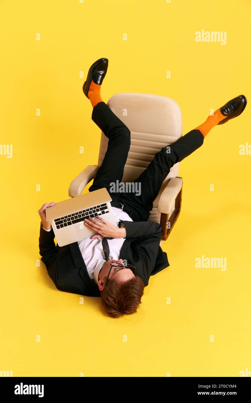 Unusual pose. Businessman, freelancer on chair working in laptop ...