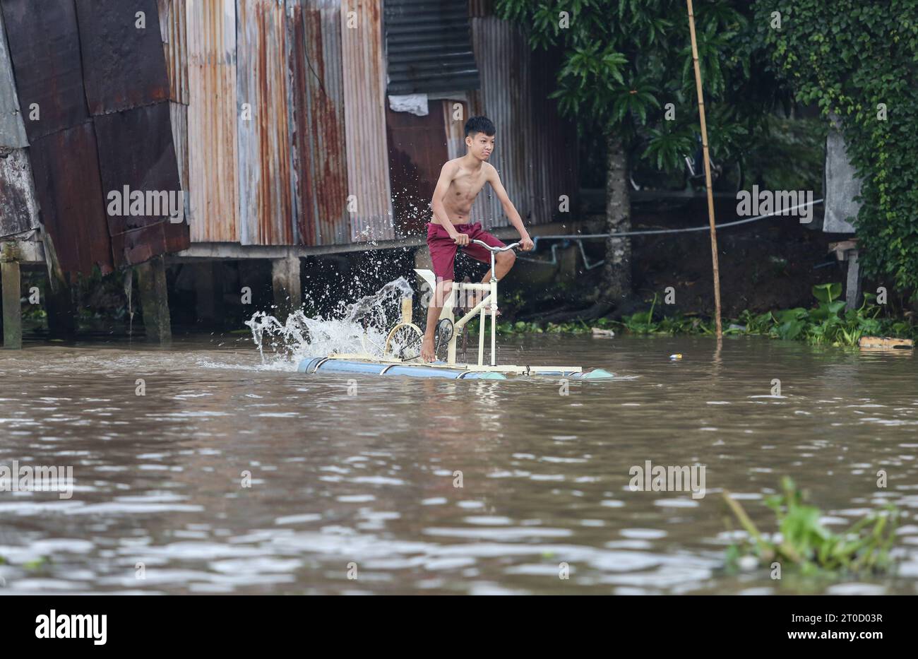 Young Vietnamese boy riding a DIY water bike on the river, Cai Be ...