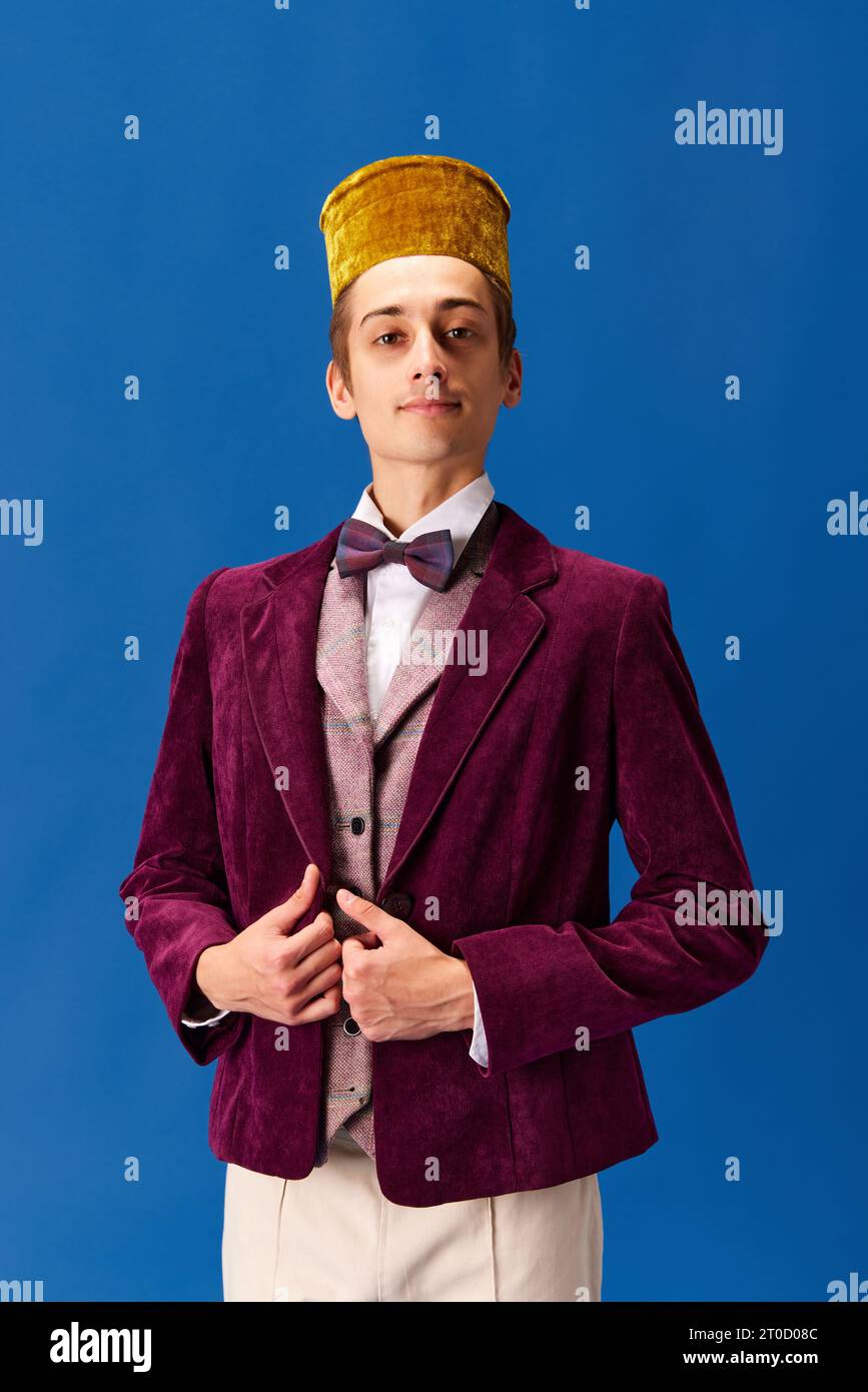 Portrait of young guy in image of hotel porter, in costume and hat ...