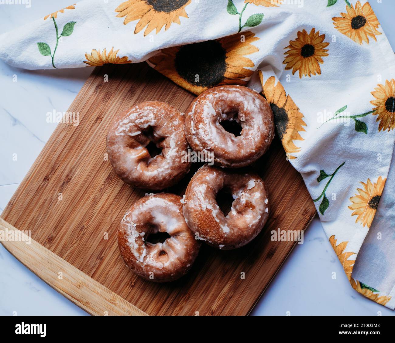 Overhead still-life image of glazed donuts with sunflower towel Stock ...