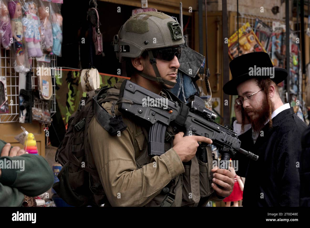 An ultra-Orthodox Jewish man watches an Israeli soldier standing guard ...