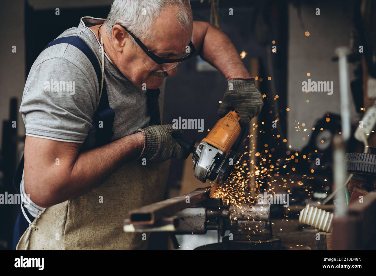 Adult master in spark protection form cuts metal with angle grinder ...