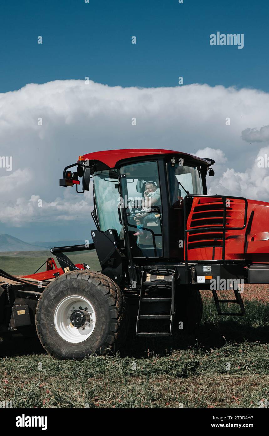 Girl waves while tractor riding with dad Stock Photo - Alamy