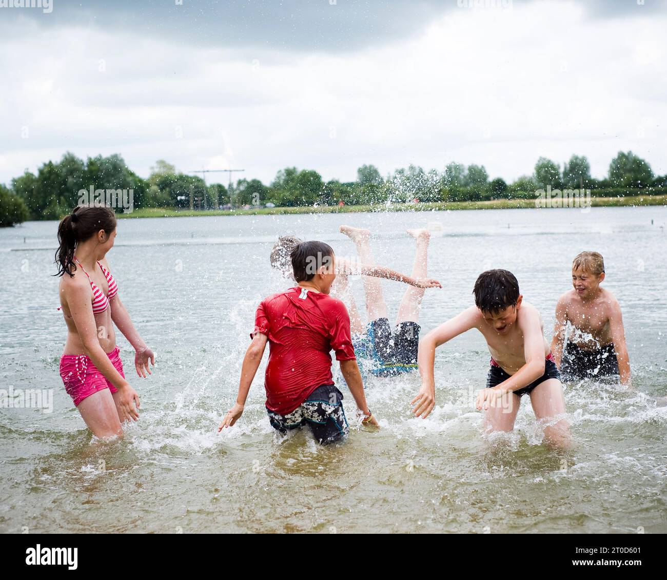 Secondary school pupils splashing in the water, in the lake, on an ...