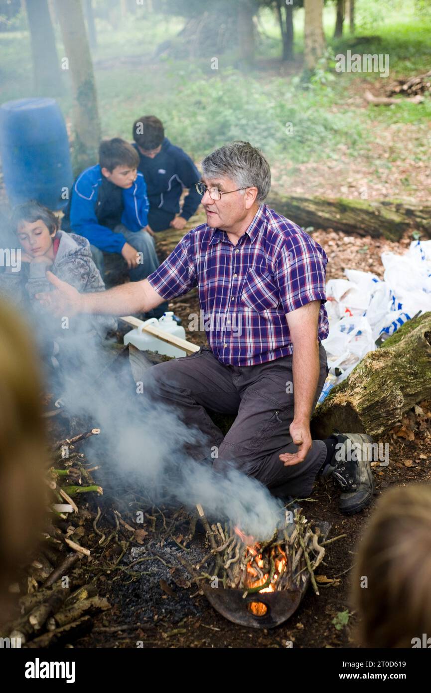 Teacher on outward bound course showing children how to light a fire ...