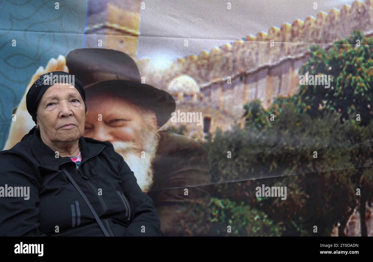 A religious Jewish woman sits next to the image of Rabbi Menachem ...