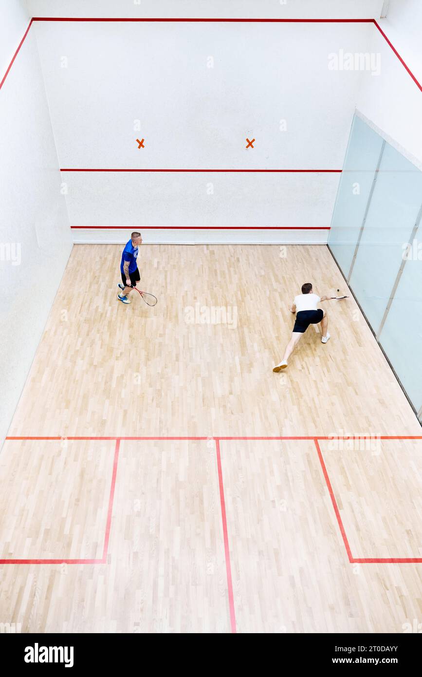 Top view of two young men, friends, sportsmen playing squash on squash ...