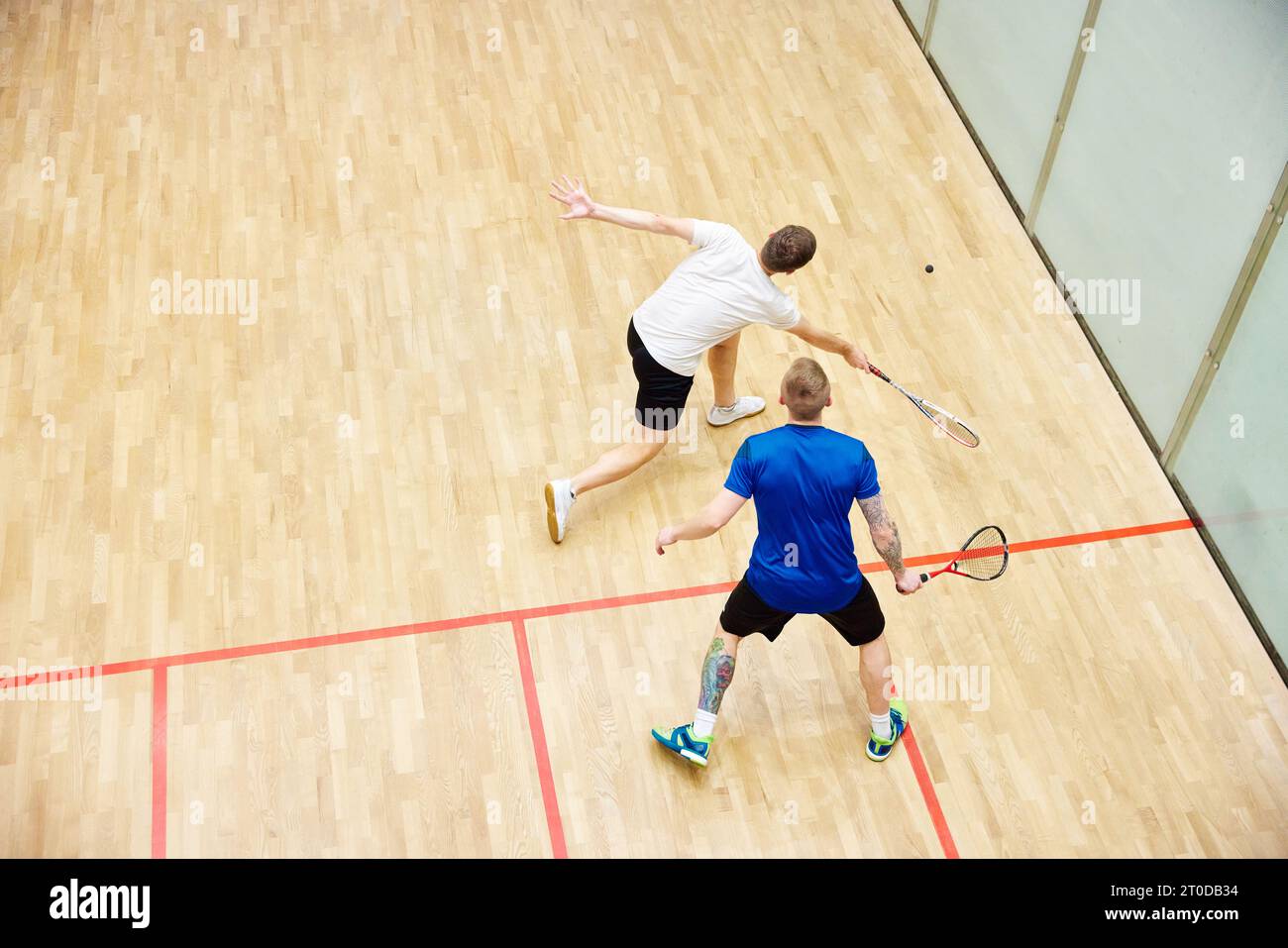 Top view of two young men, friends, sportsmen playing squash on squash ...