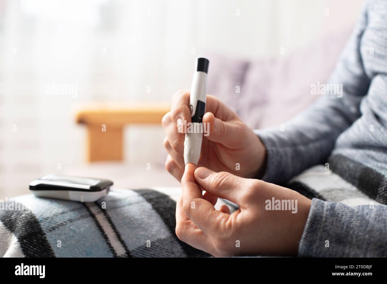 Middle age caucasian man sitting on the sofa going to pierce his finger ...
