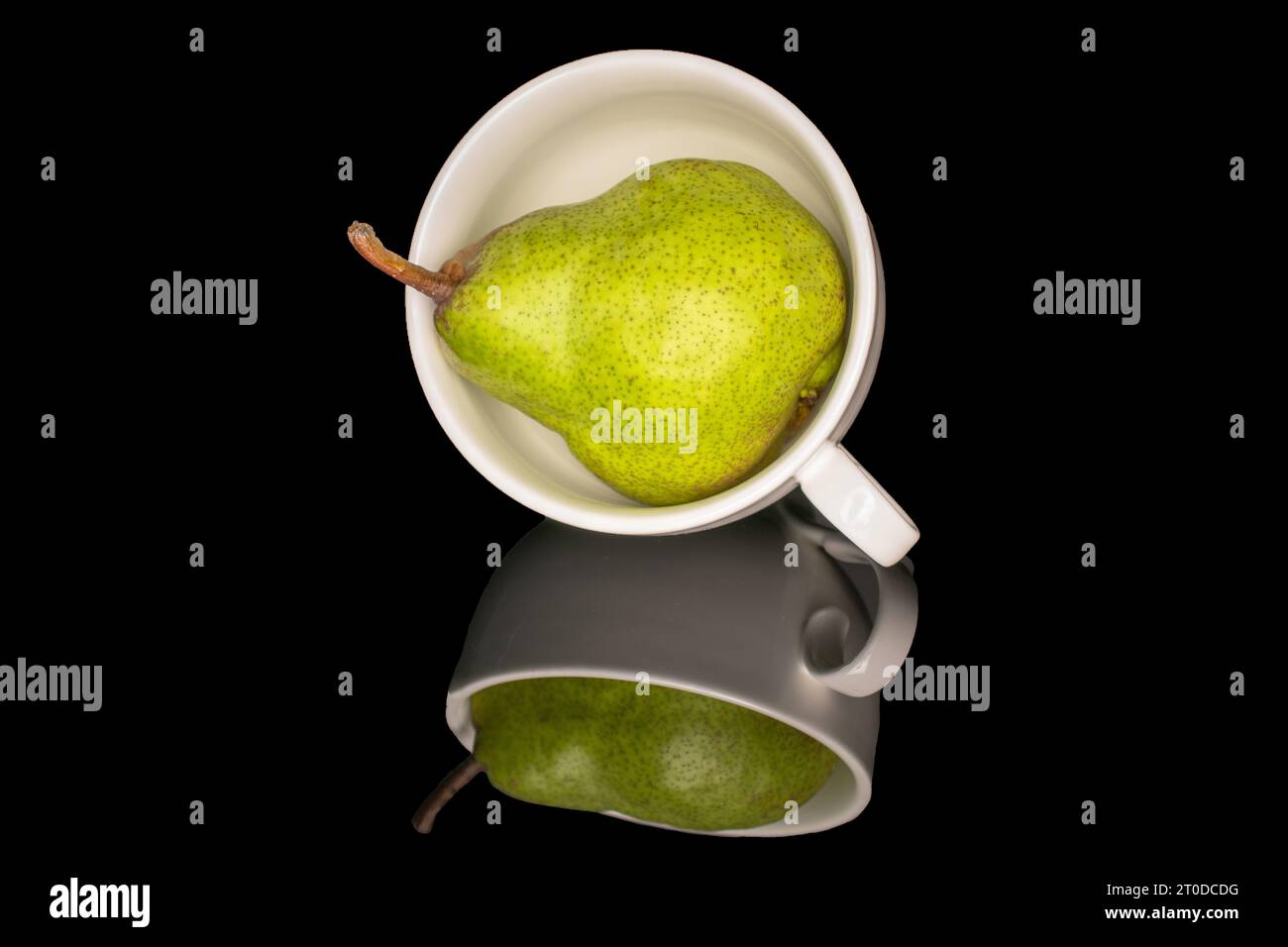 One natural pear with a white cup, close-up, on a black background ...