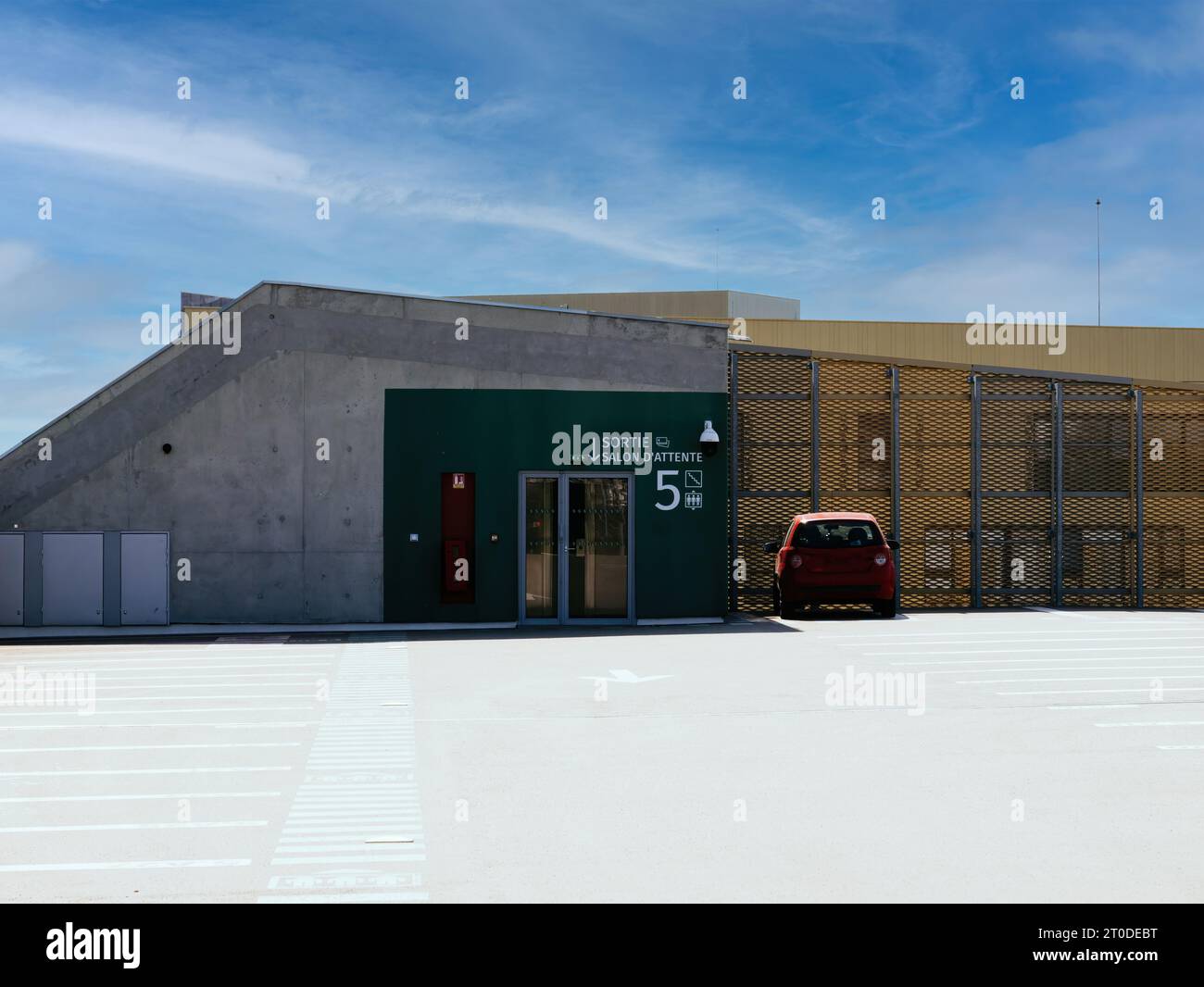 An isolated red car is parked on the left-hand side at the exit of a ...