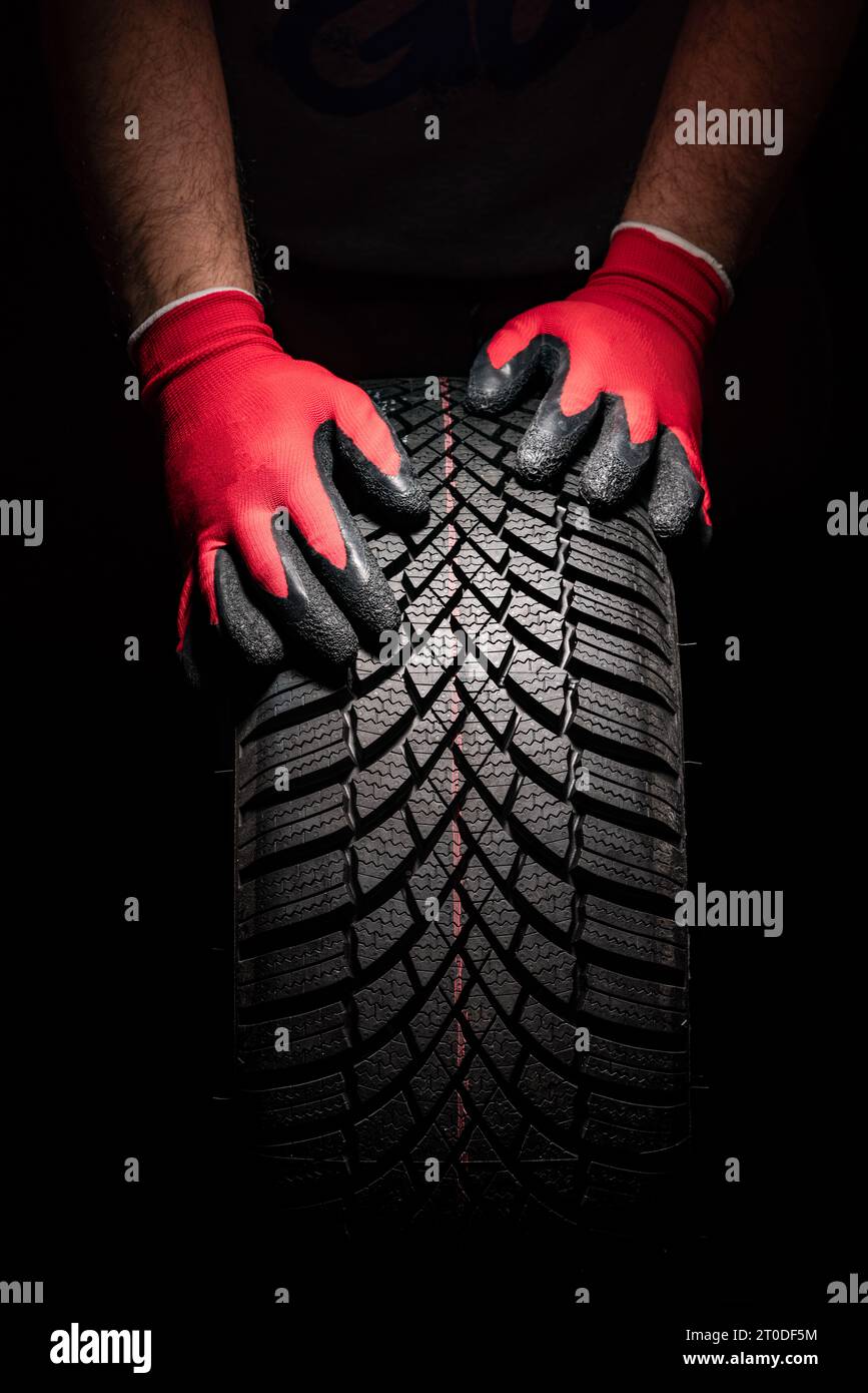 Car tire service and hands of mechanic holding new tyre on black ...