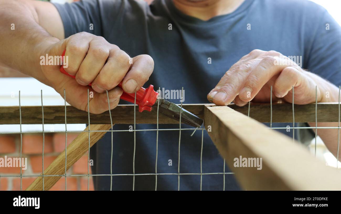 installation of a bird cage by a man with pliers, fixing a metal ...