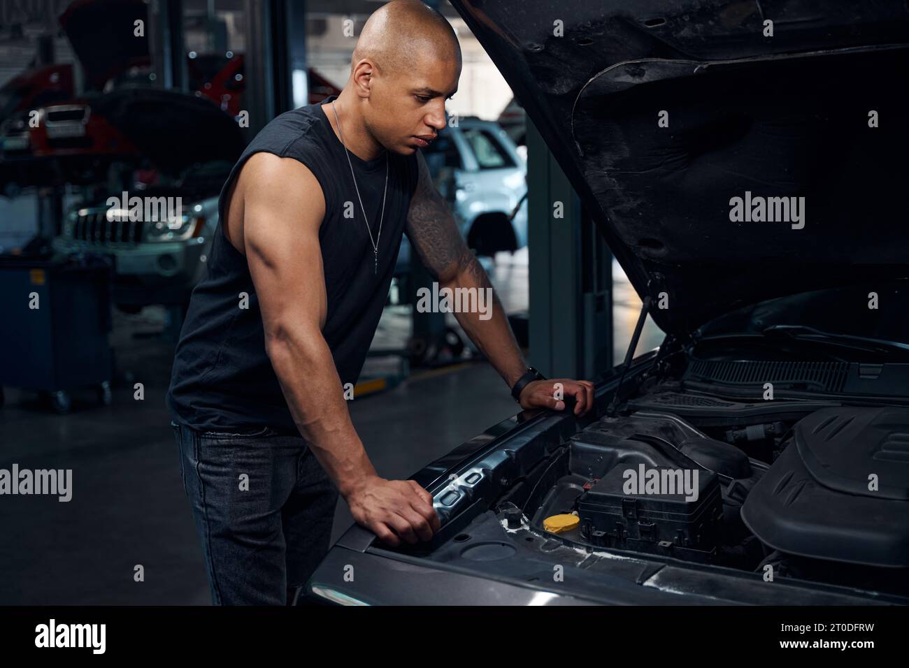 Masculine man worker of vehicle service station standing near luxury ...