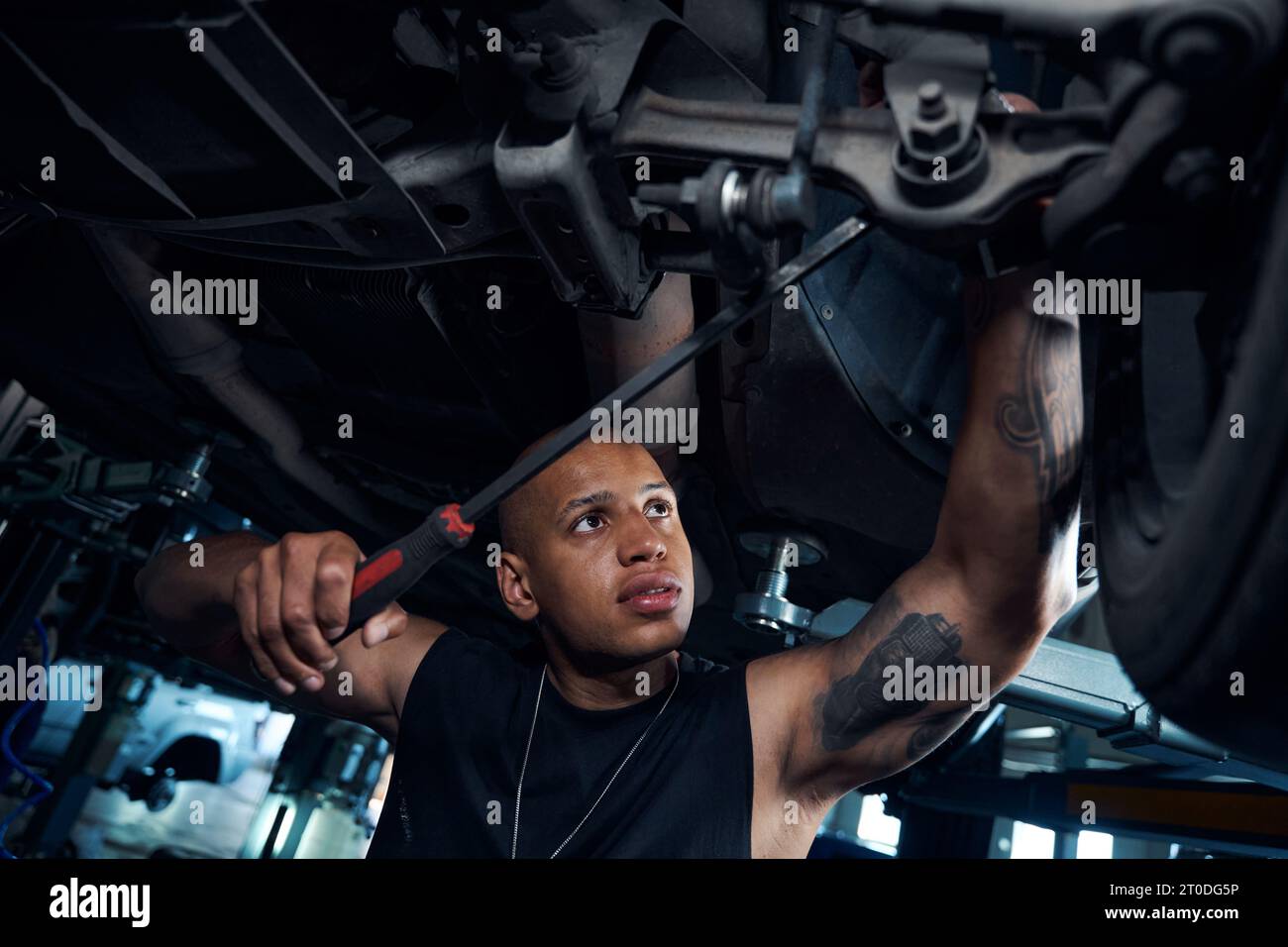 African American auto-mechanic repairing and maintaining car chassis ...