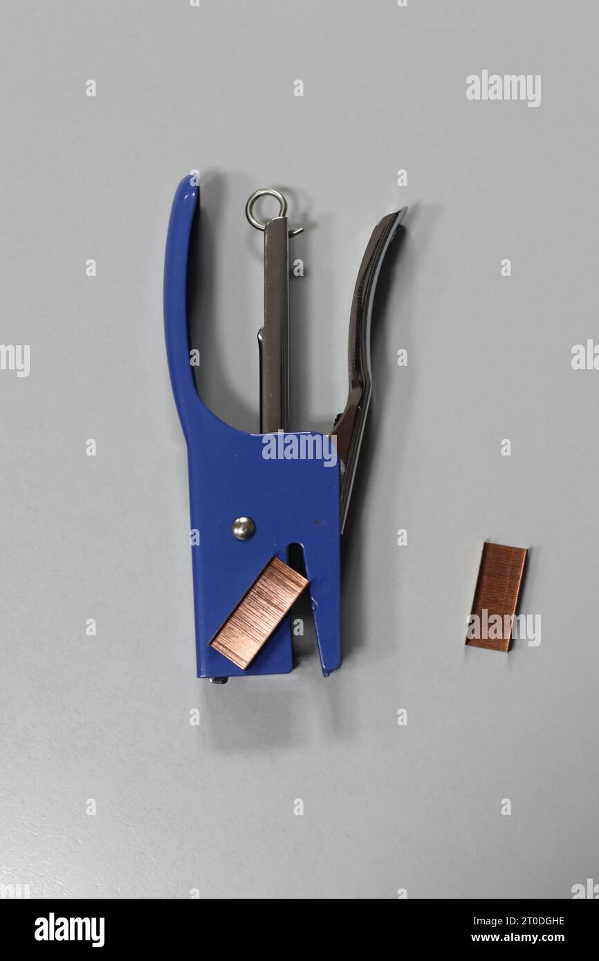 A blue stapler perched atop a shining piece of copper radiates a ...