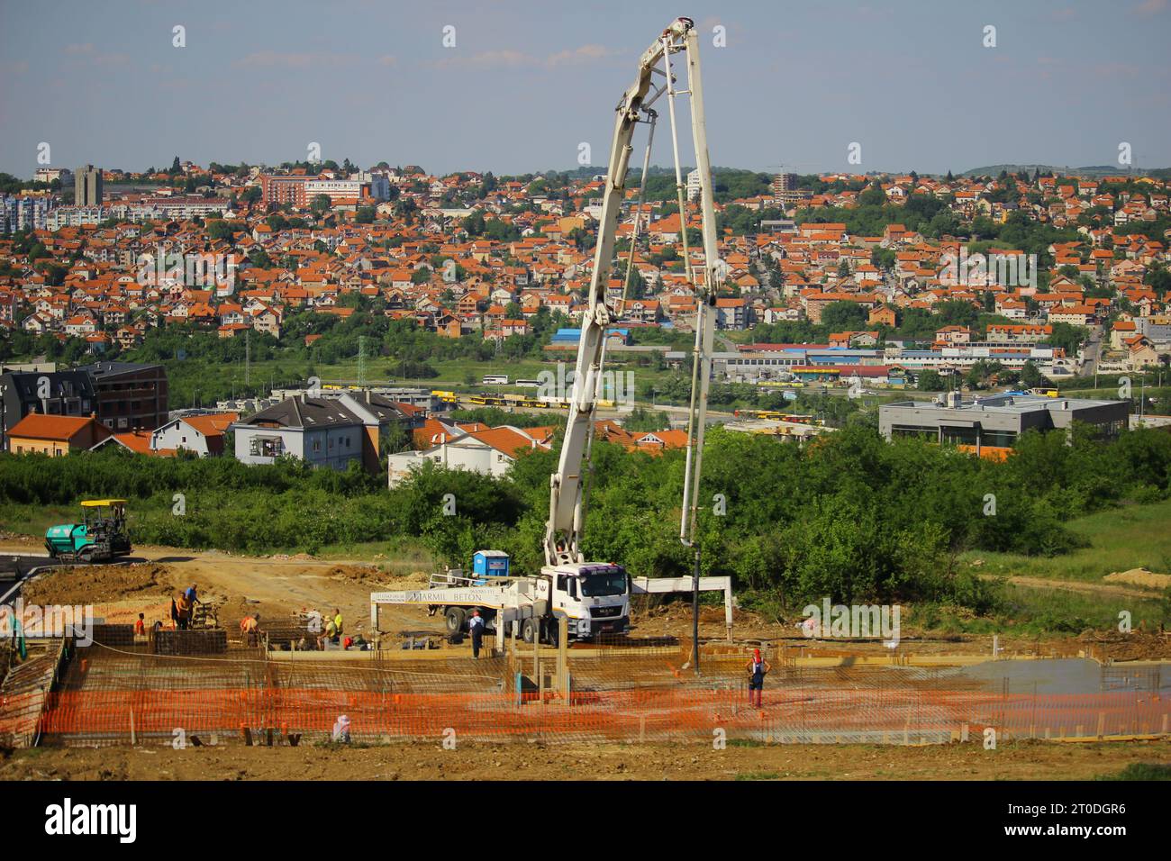 On a bright, sunny day, a towering crane looms over a bustling ...
