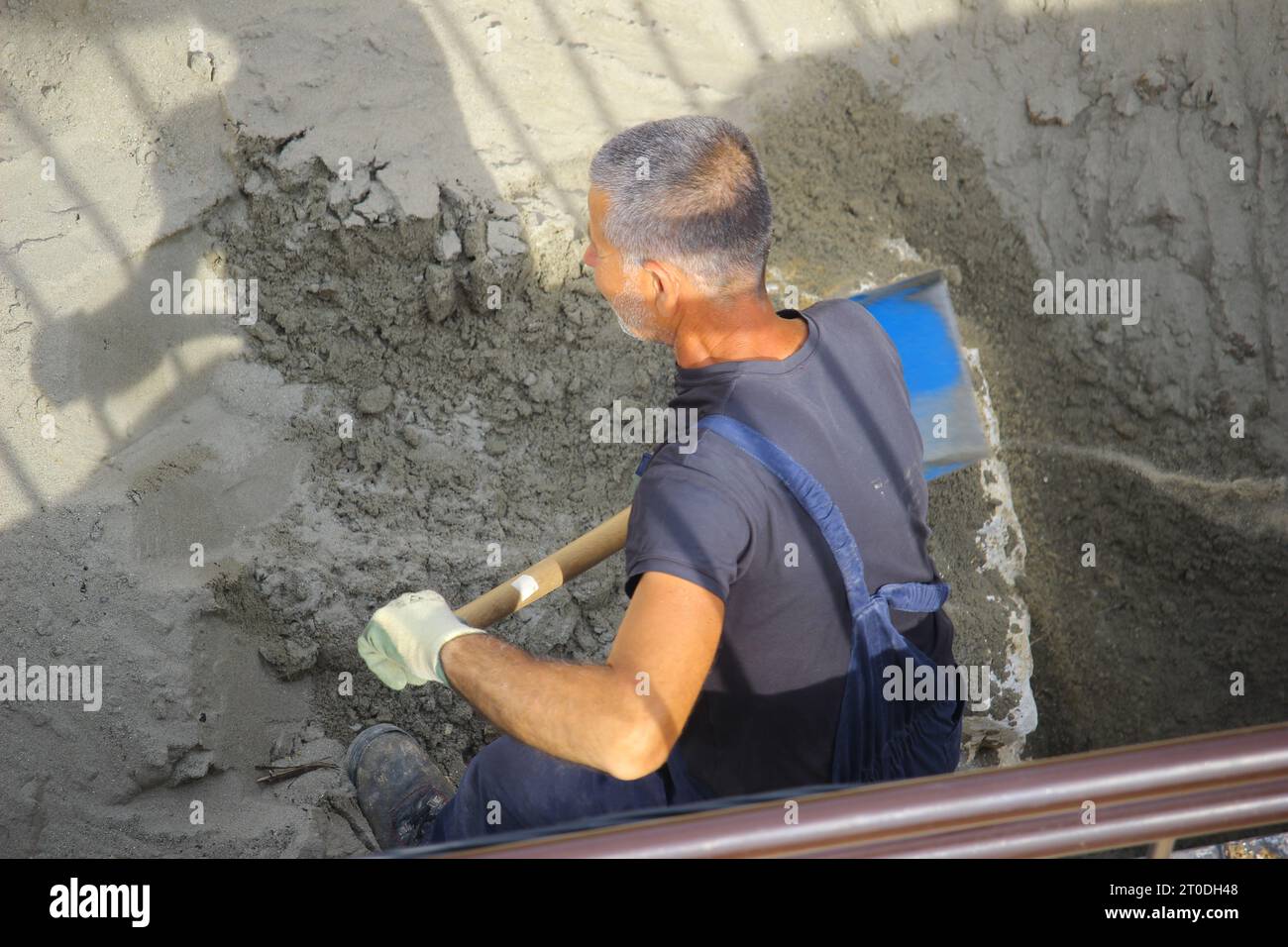 A rugged man in overalls stands on a dusty street, passionately ...