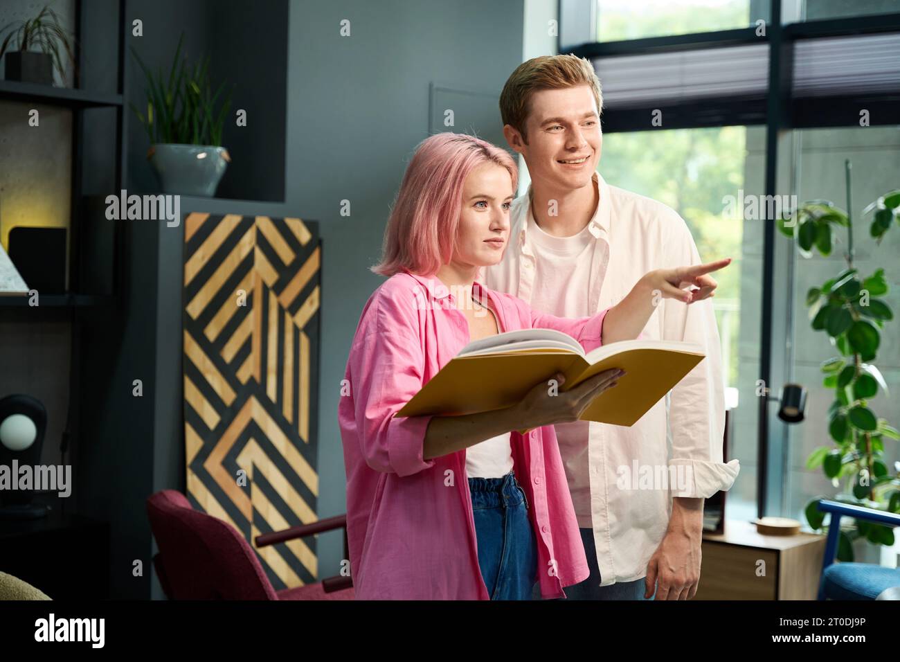 Young people look at samples in a yellow book Stock Photo - Alamy